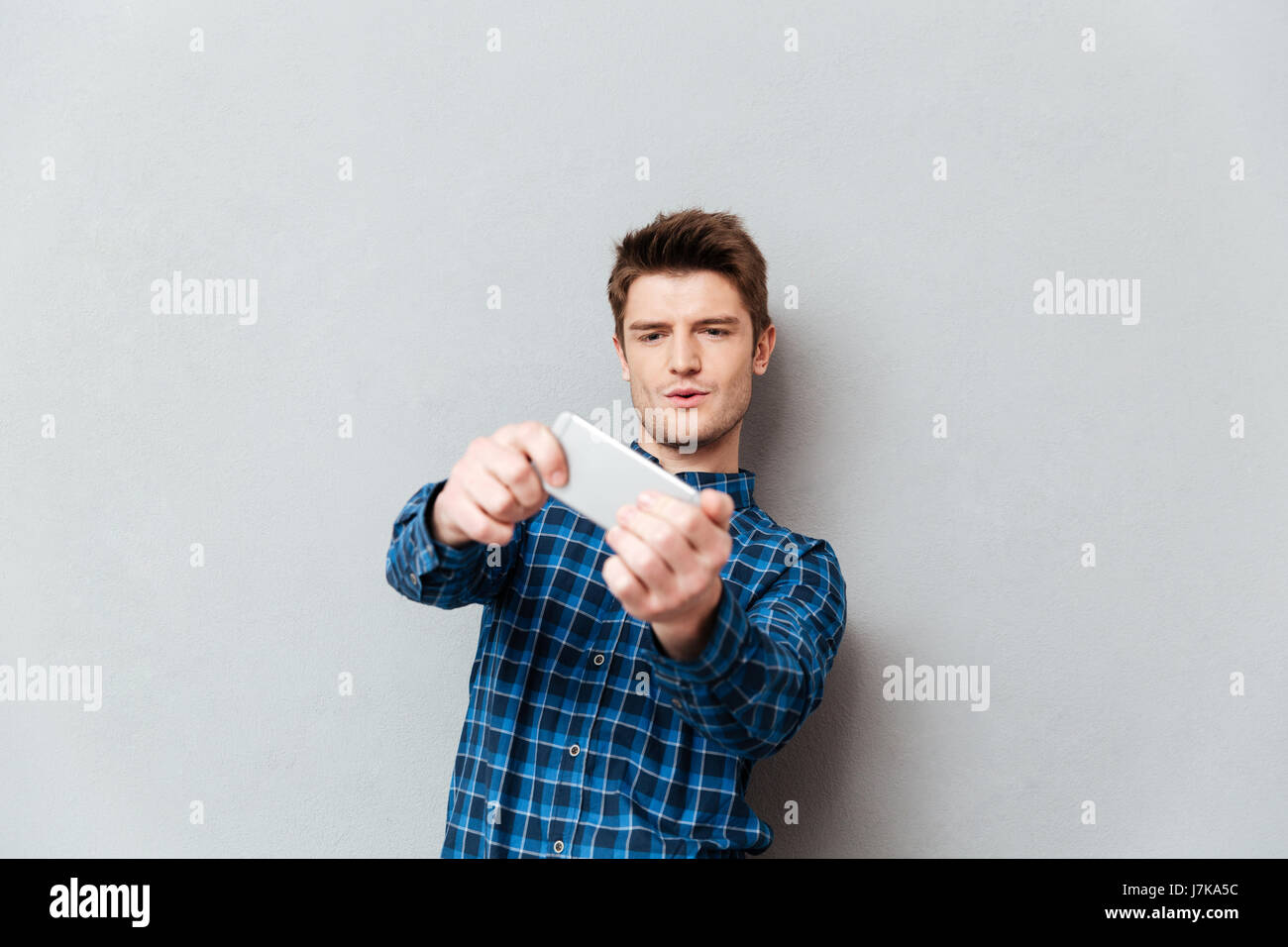 Young serious man playing smartphone games isolated over grey Stock ...