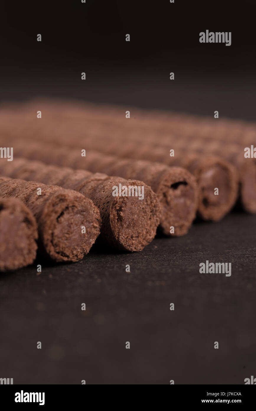 Close up of chocolate waffle rolls in a row over wooden surface Stock ...