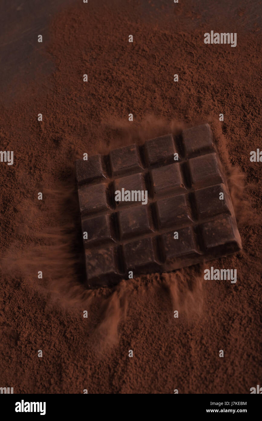 Dark chocolate bar falling in chocolate powder on a table Stock Photo ...