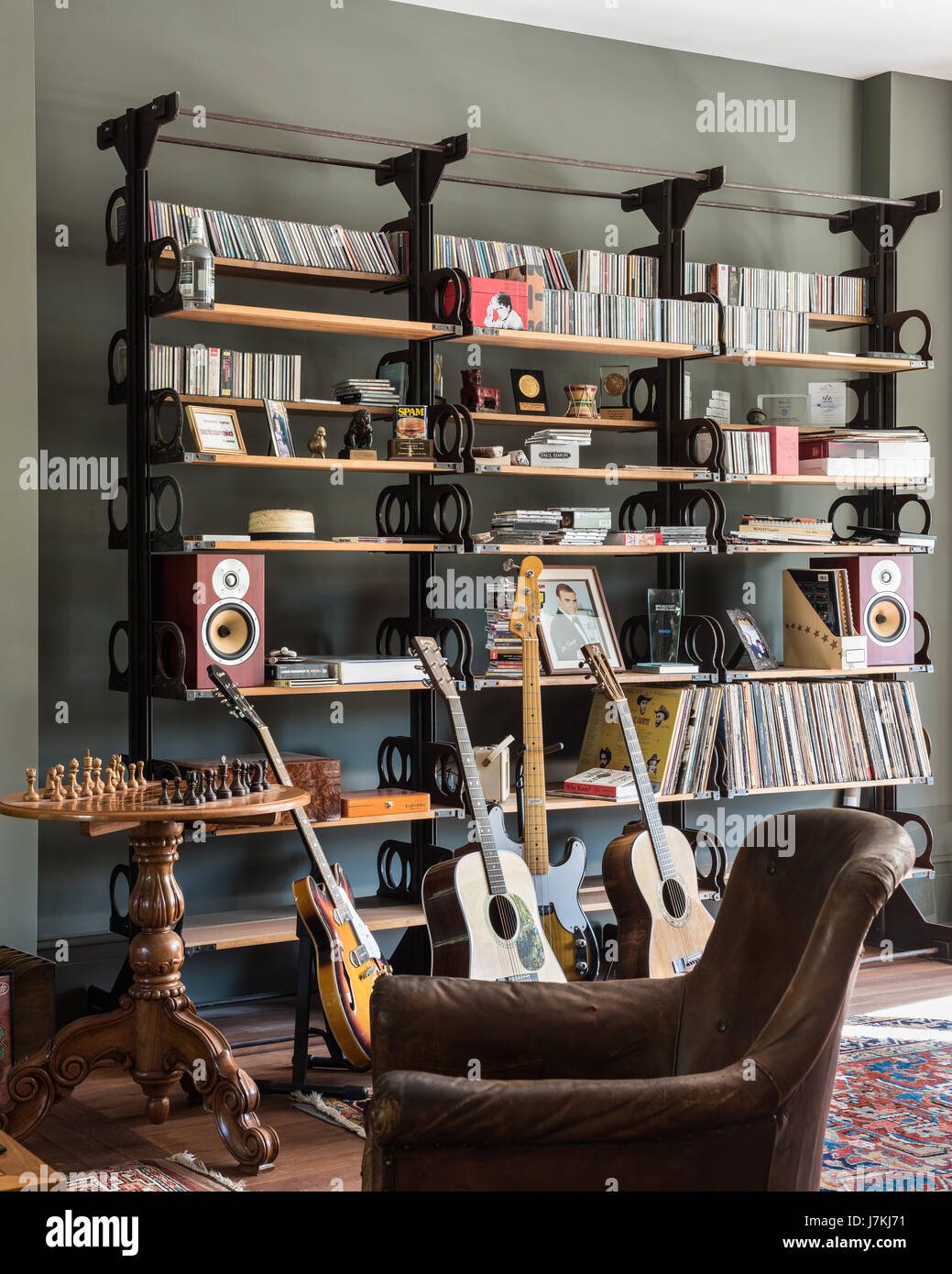 A guitar collection in front of a set of adjustable cast iron shelving ...