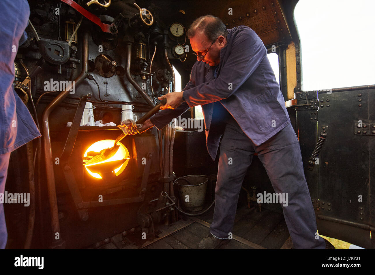 Fireman fuelling boiler on vintage steam train foot plate Stock Photo ...