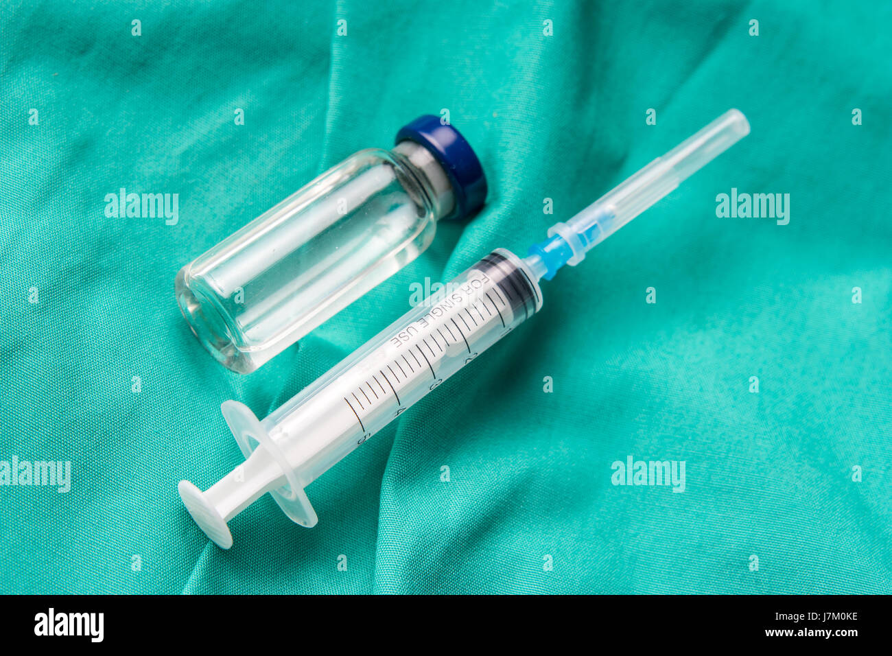 Medical syringe and vials lying on the hospital's green background. The ...