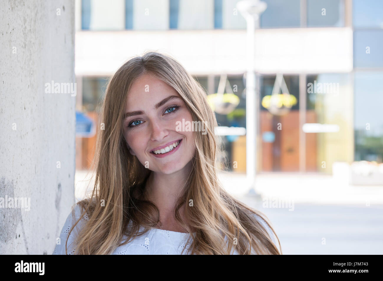 Portrait of smiling young woman as university student on college campus ...