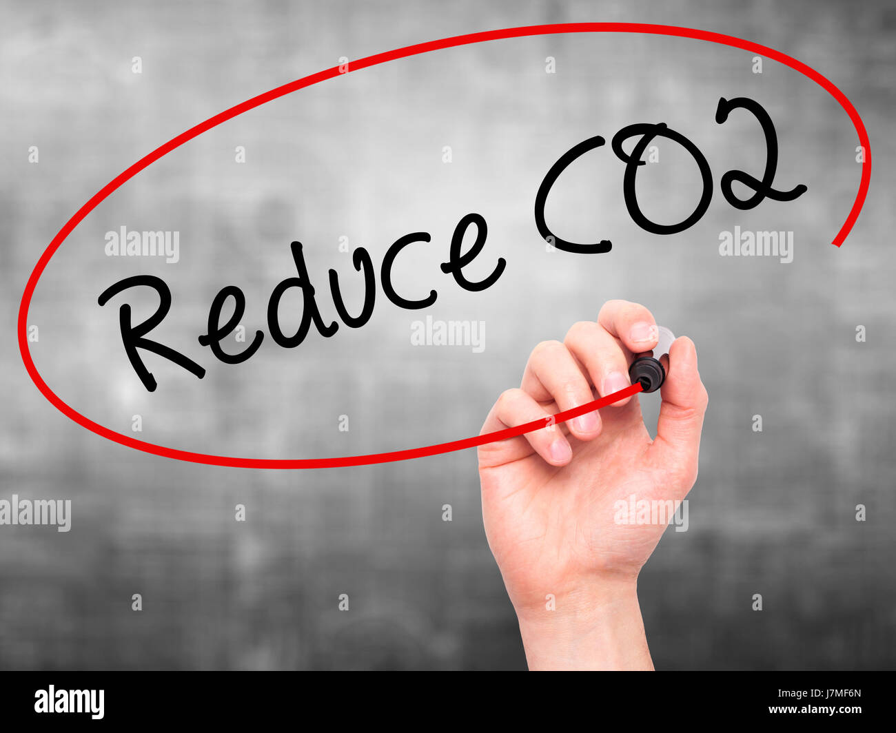 Man Hand writing Reduce CO2 with black marker on visual screen ...