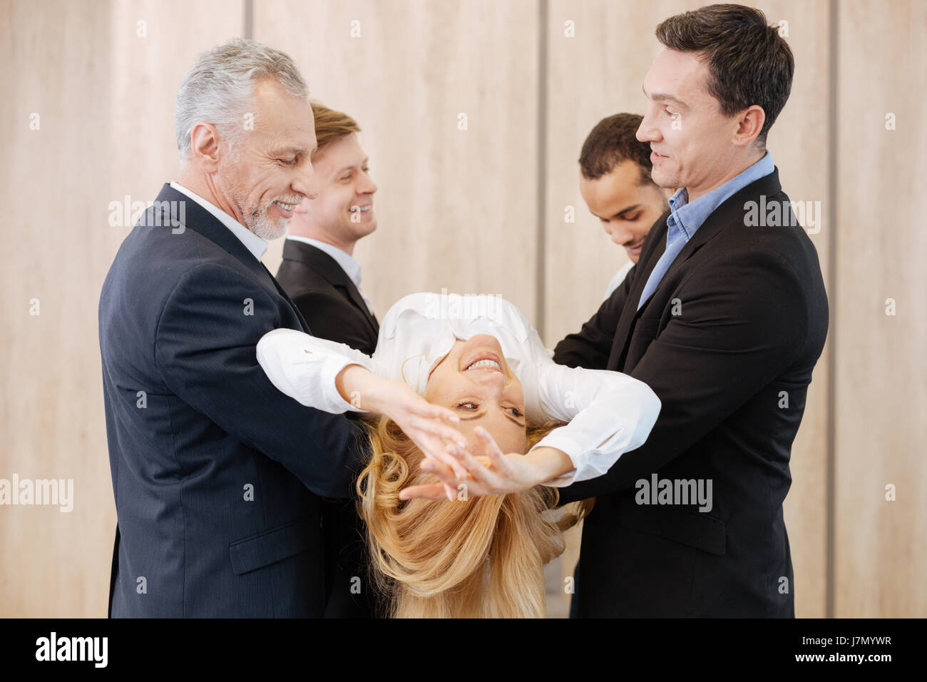 Happy beautiful woman being held by her colleagues Stock Photo - Alamy