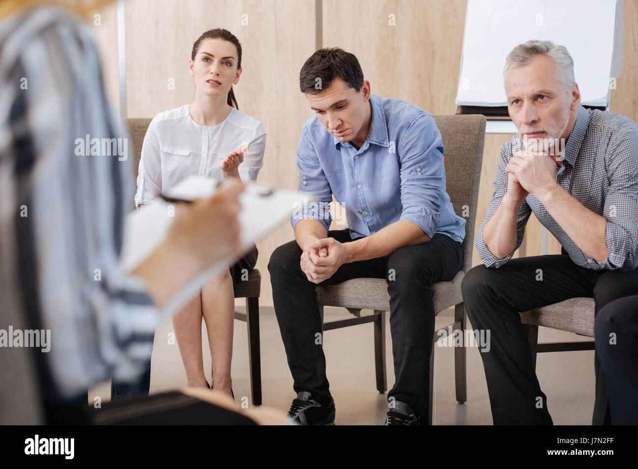 Serious adult people sitting on the chairs Stock Photo - Alamy