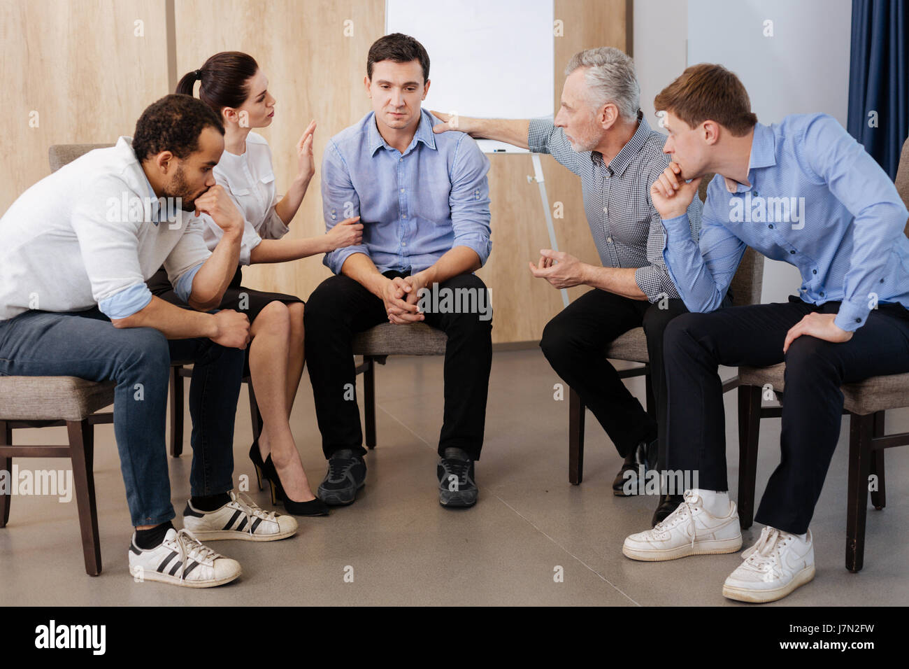 Friendly sympathetic people supporting a sad man Stock Photo - Alamy