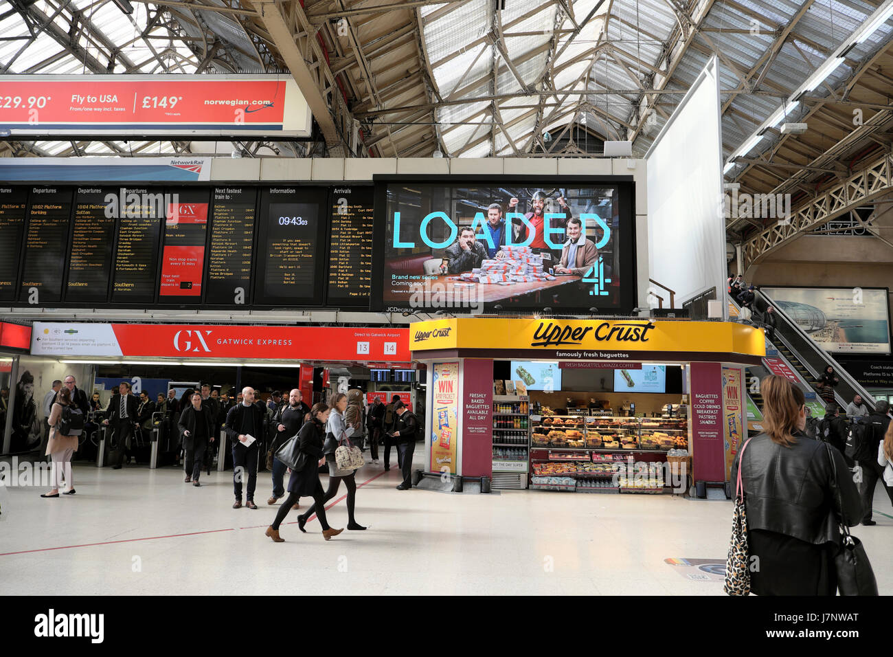 People walking past the electronic billboard display and Upper Crust ...