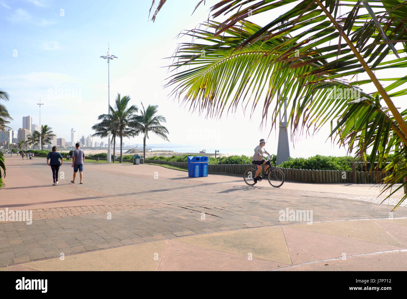 People walk along the promenade and a cyclist rides past all enjoying ...