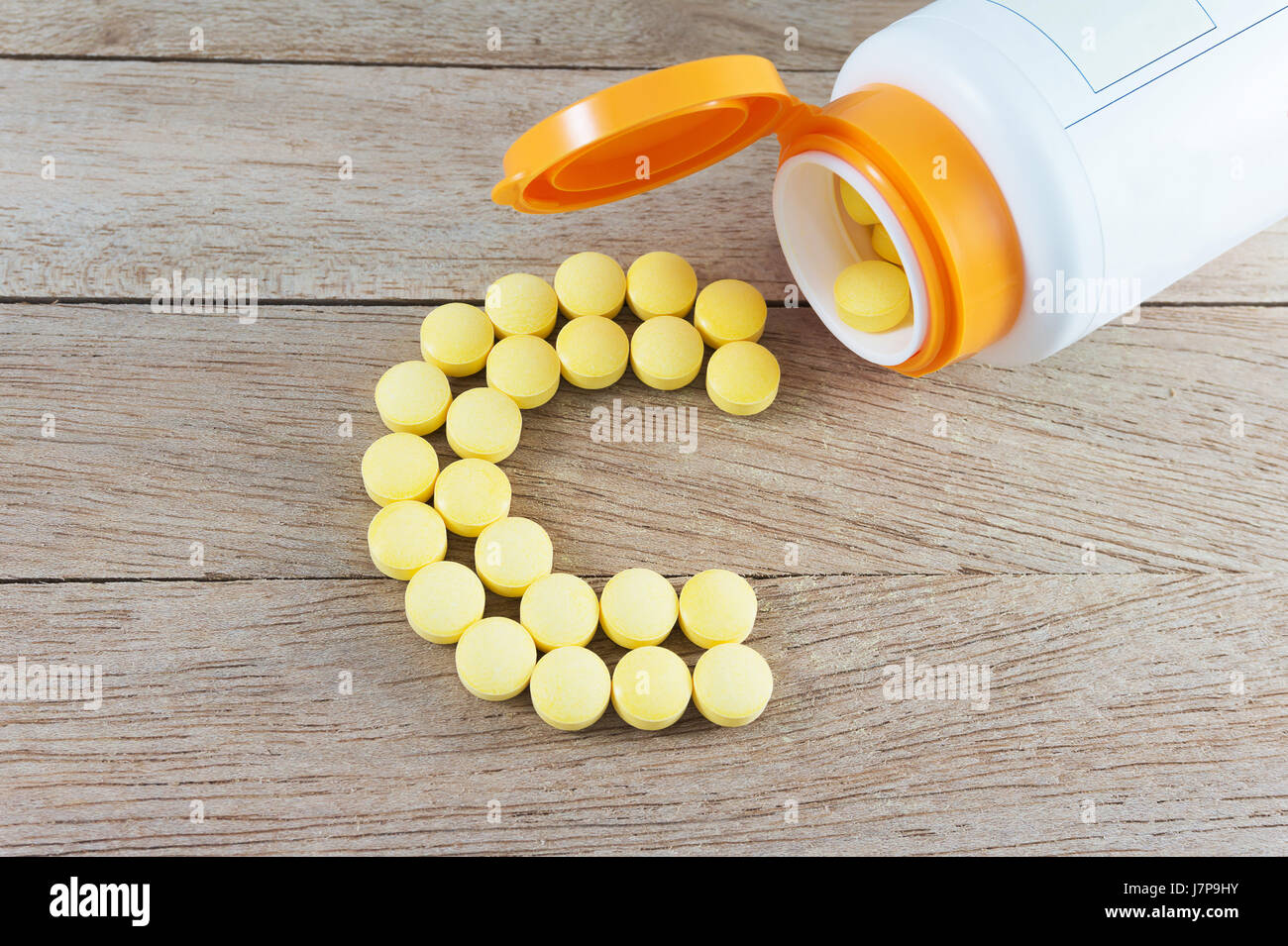 Yellow pills forming shape to C alphabet on wood background Stock Photo ...