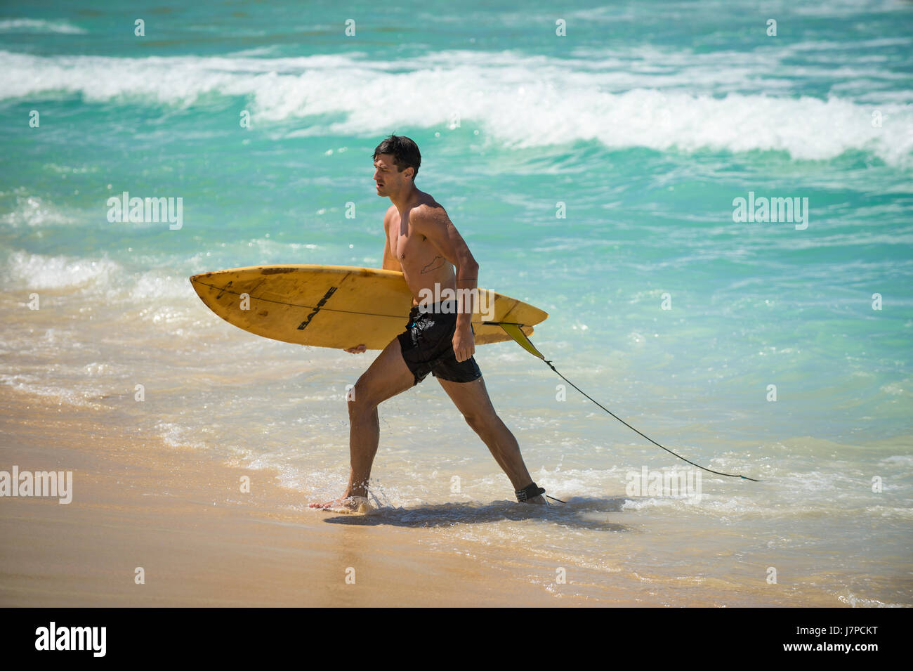 RIO DE JANEIRO - FEBRUARY 6, 2017: Young Brazilian surfer walks with ...
