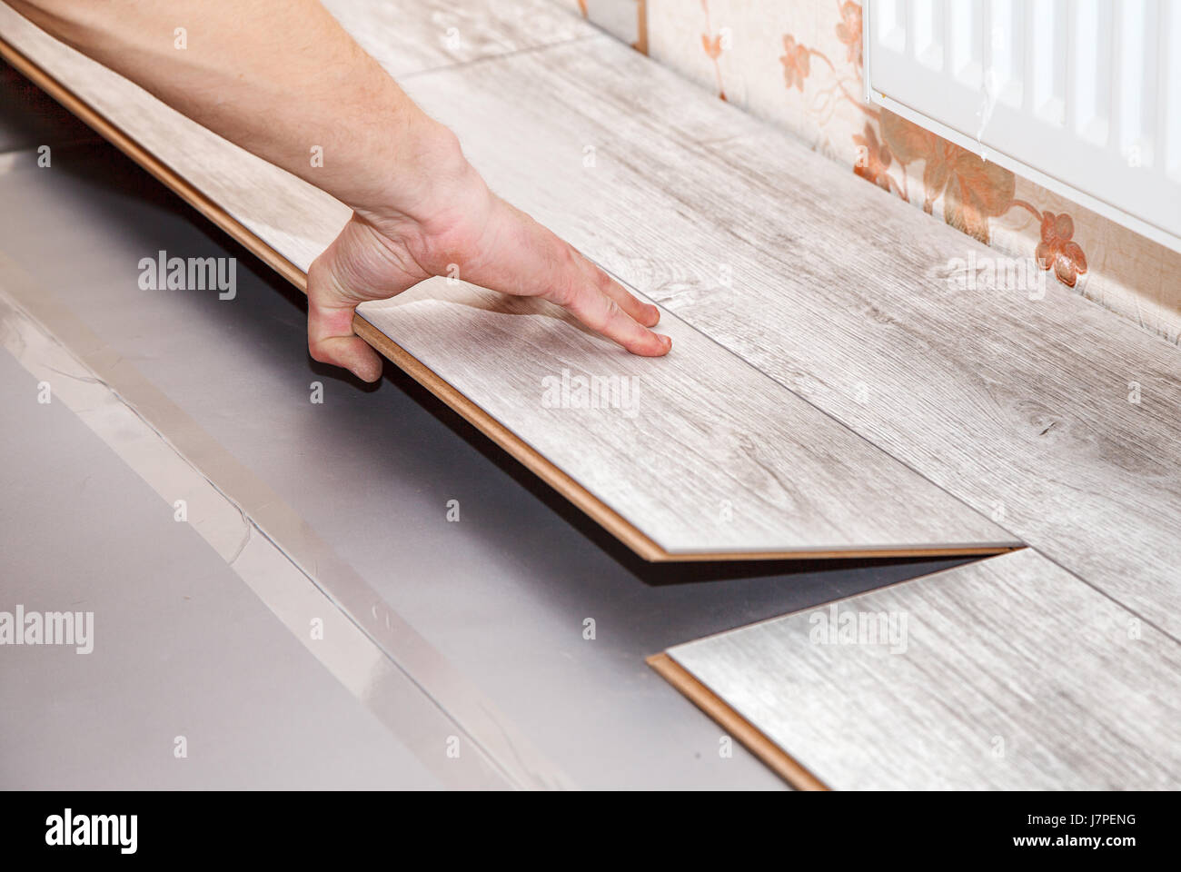 young handyman installing wooden floor in new house, hands closeup ...