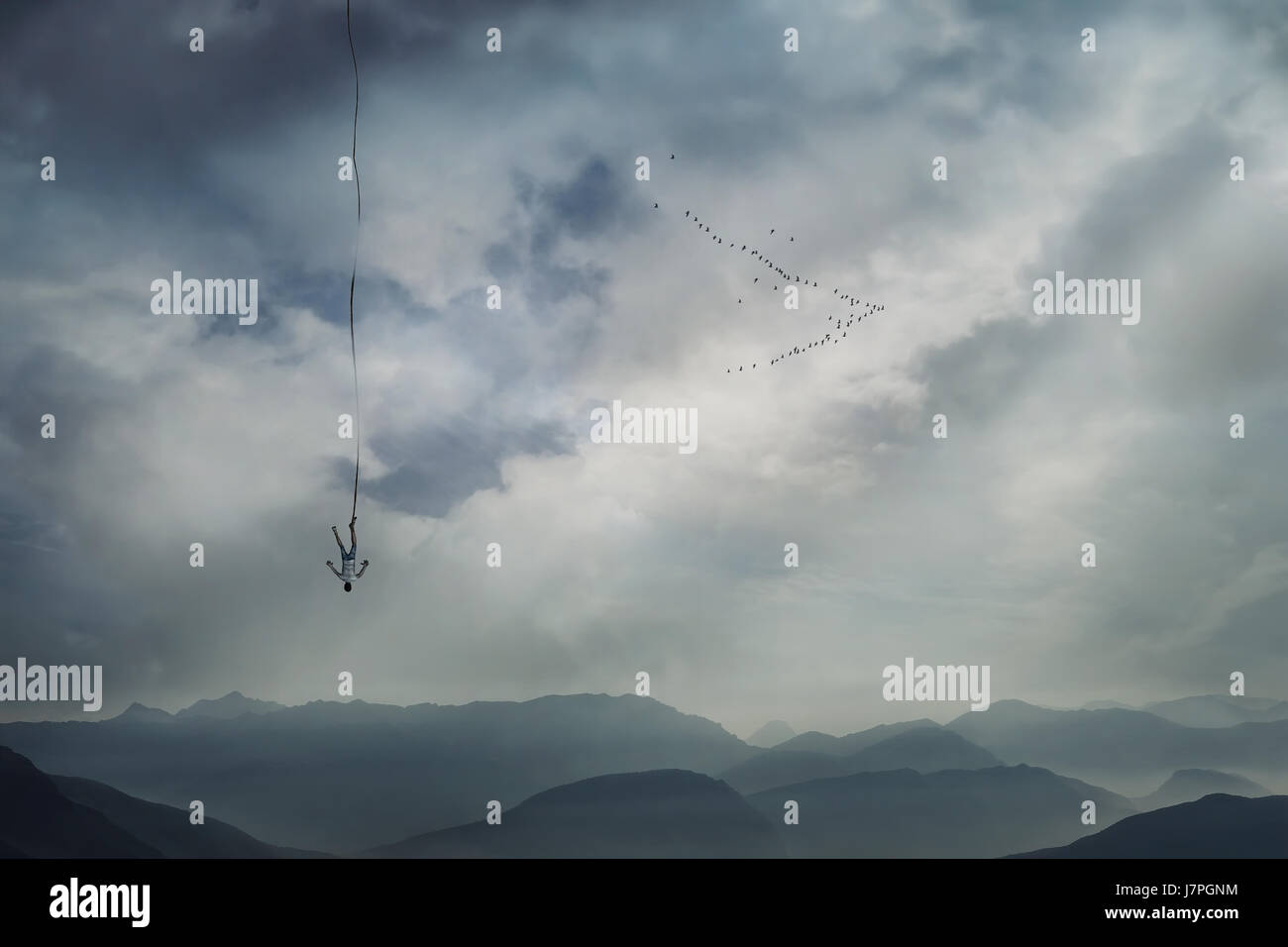 Young man falling from the sky with a rope tied to his leg as safety ...