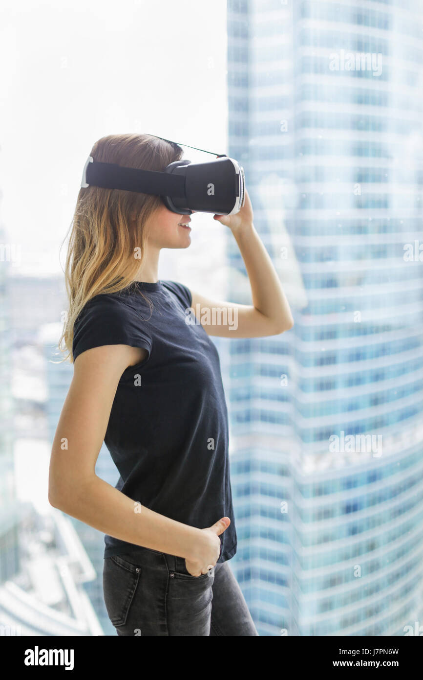 Young woman wearing vr glasses against window Stock Photo - Alamy