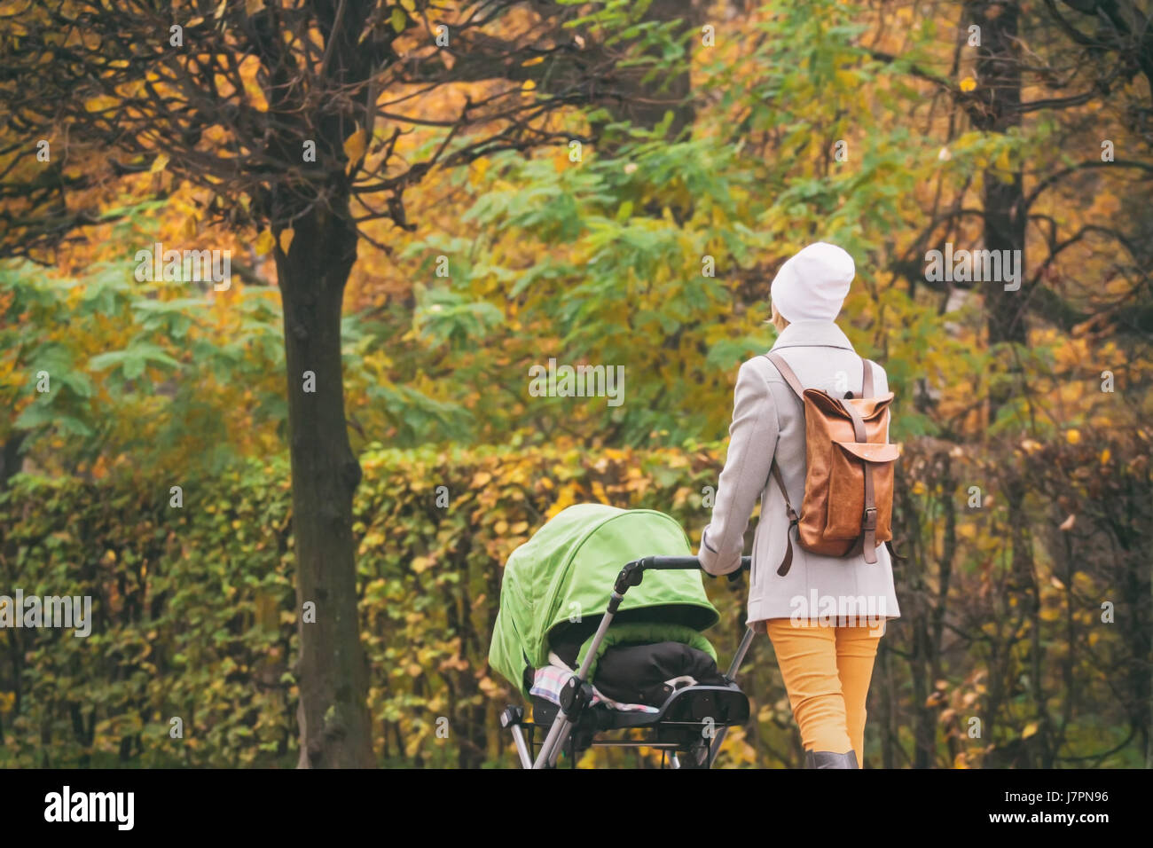 Young mother pushing stroller in autumn park Stock Photo - Alamy