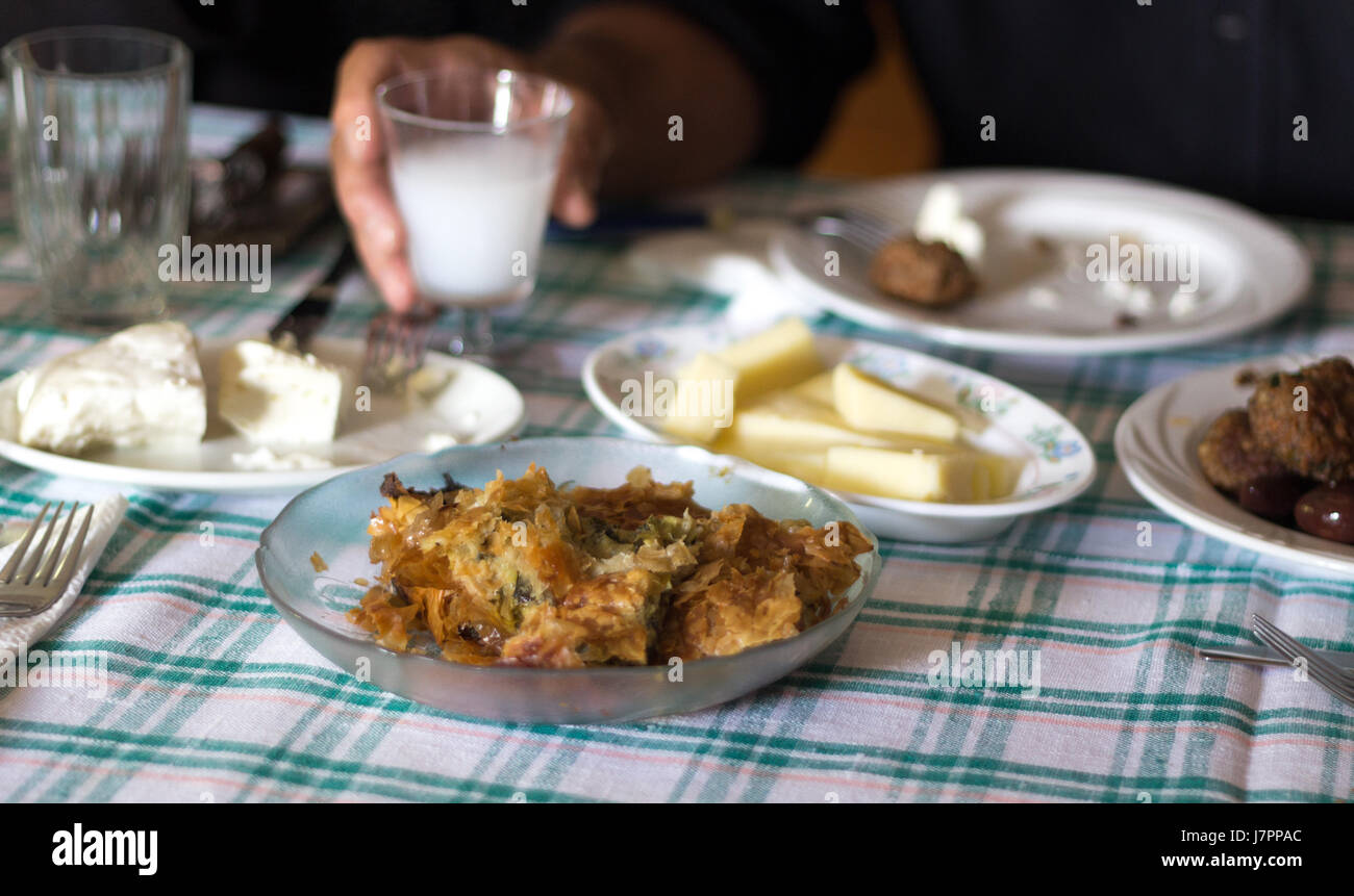 A greek lunch at home with feta cheese, ouzo and spinach pie on a table ...