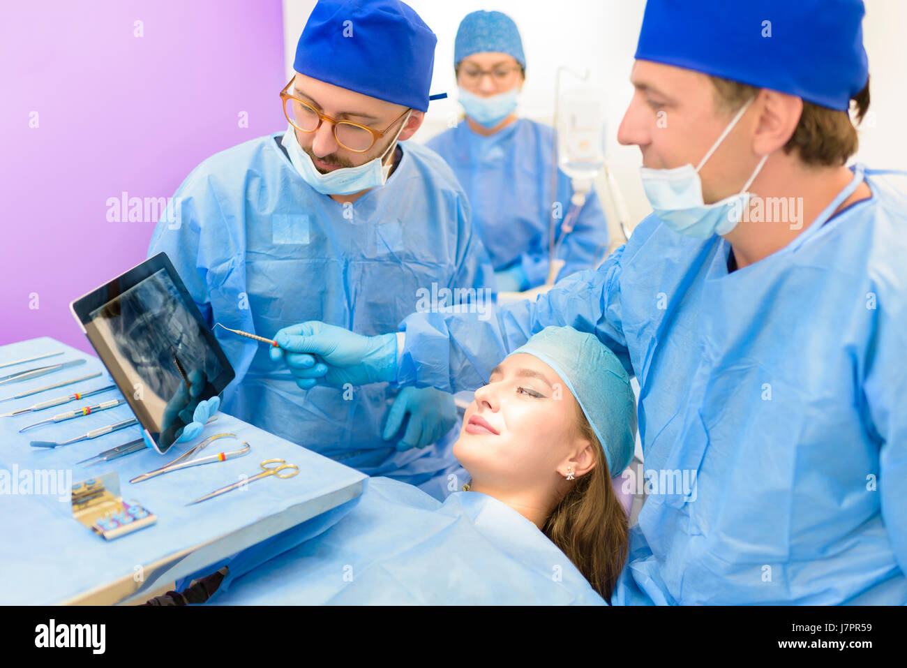 Dental team examining radiography of a young beautiful woman patient ...