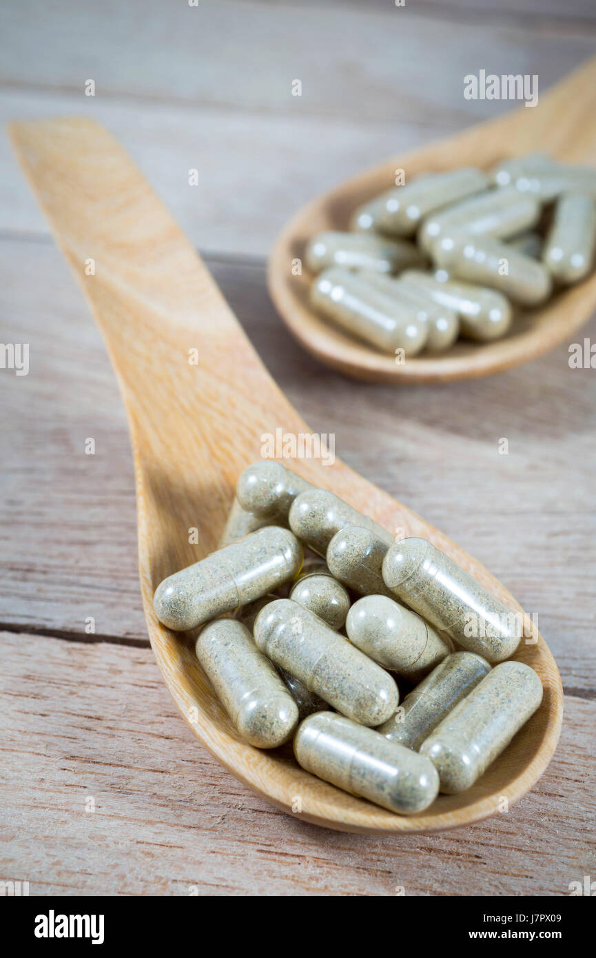 Capsule pills in wooden spoon on wood background Stock Photo - Alamy