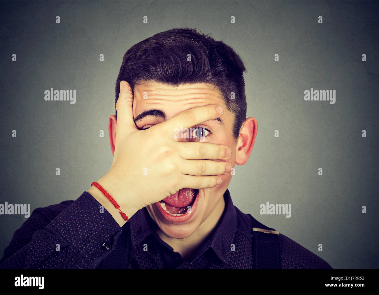 man looking surprised in disbelief, with hand on face looking at camera ...
