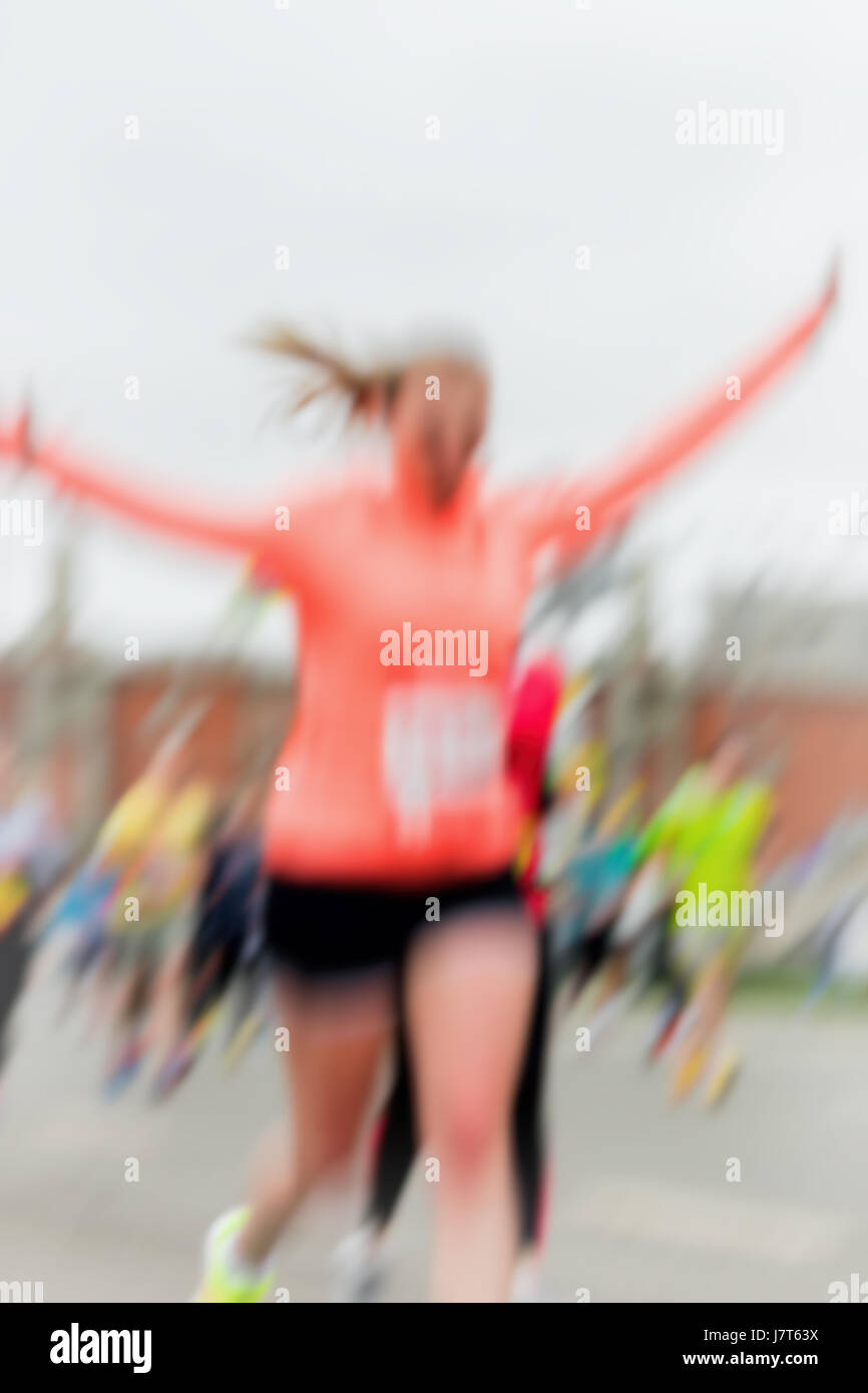 Happy girl runner winning race in group of sportsmen running marathon ...