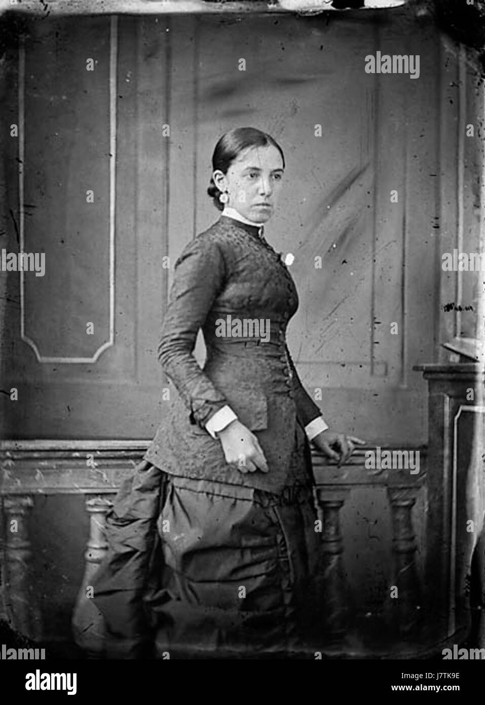 Photograph of a young woman standing, captured in a moment of stillness ...