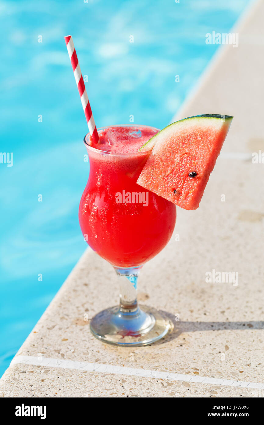 Glass of fresh watermelon smoothie juice drink on border of a swimming ...