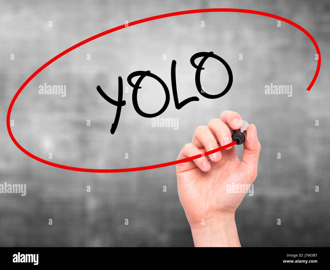 Man Hand writing YOLO (You Only Live Once) with black marker on visual ...