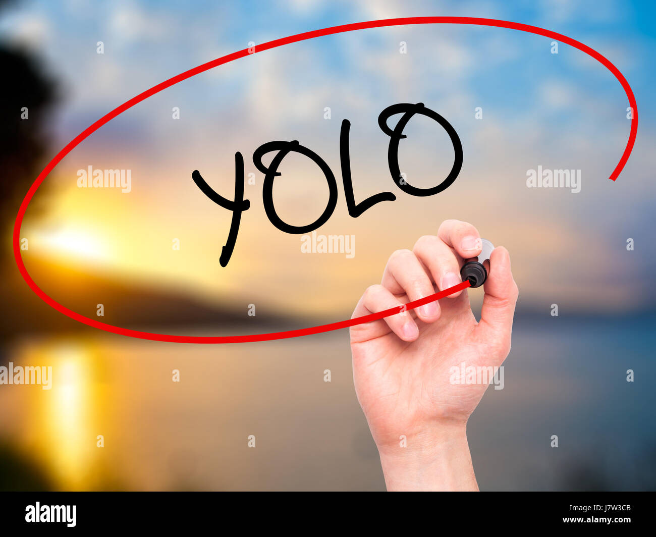 Man Hand writing YOLO (You Only Live Once) with black marker on visual ...