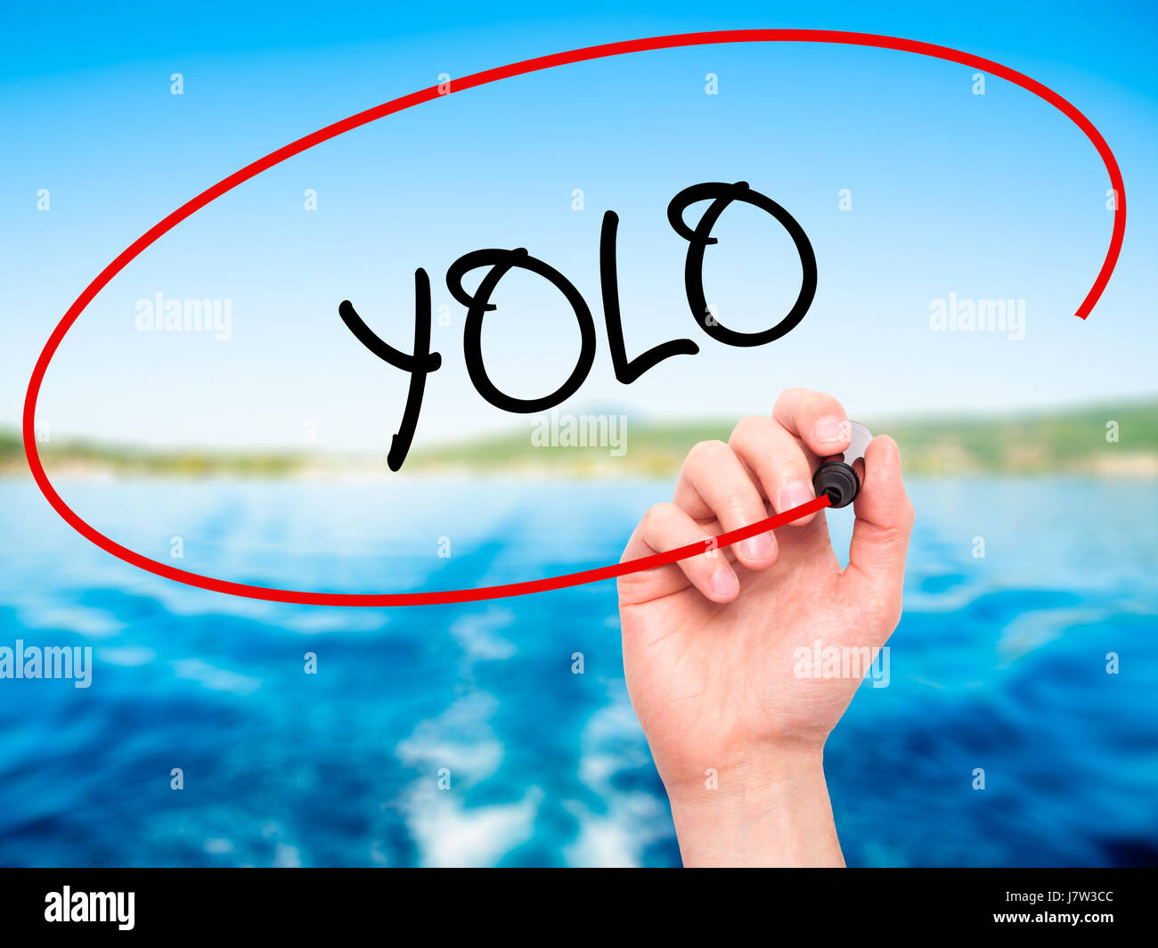 Man Hand writing YOLO (You Only Live Once) with black marker on visual ...