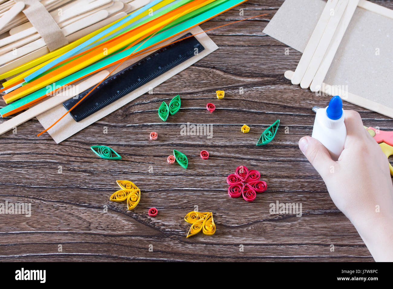 The child glues the details of the flowers in quilling technique to the ...