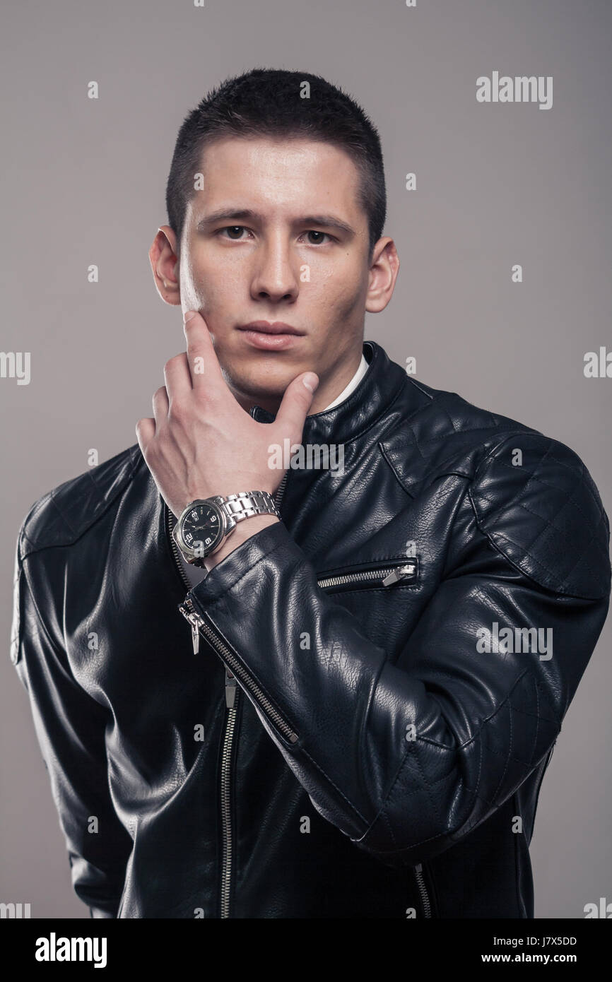 one young adult man only, hand touching face, blank expression, leather ...