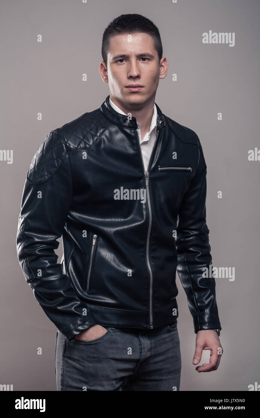 one young adult man only, looking to the camera, looking tense, leather ...