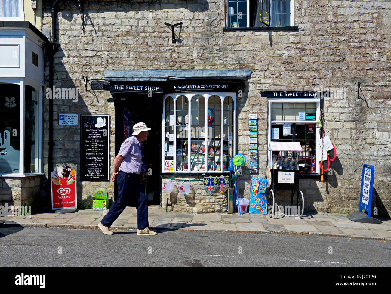Man walking past sweet shop in the village of Corfe Castle, Dorset ...