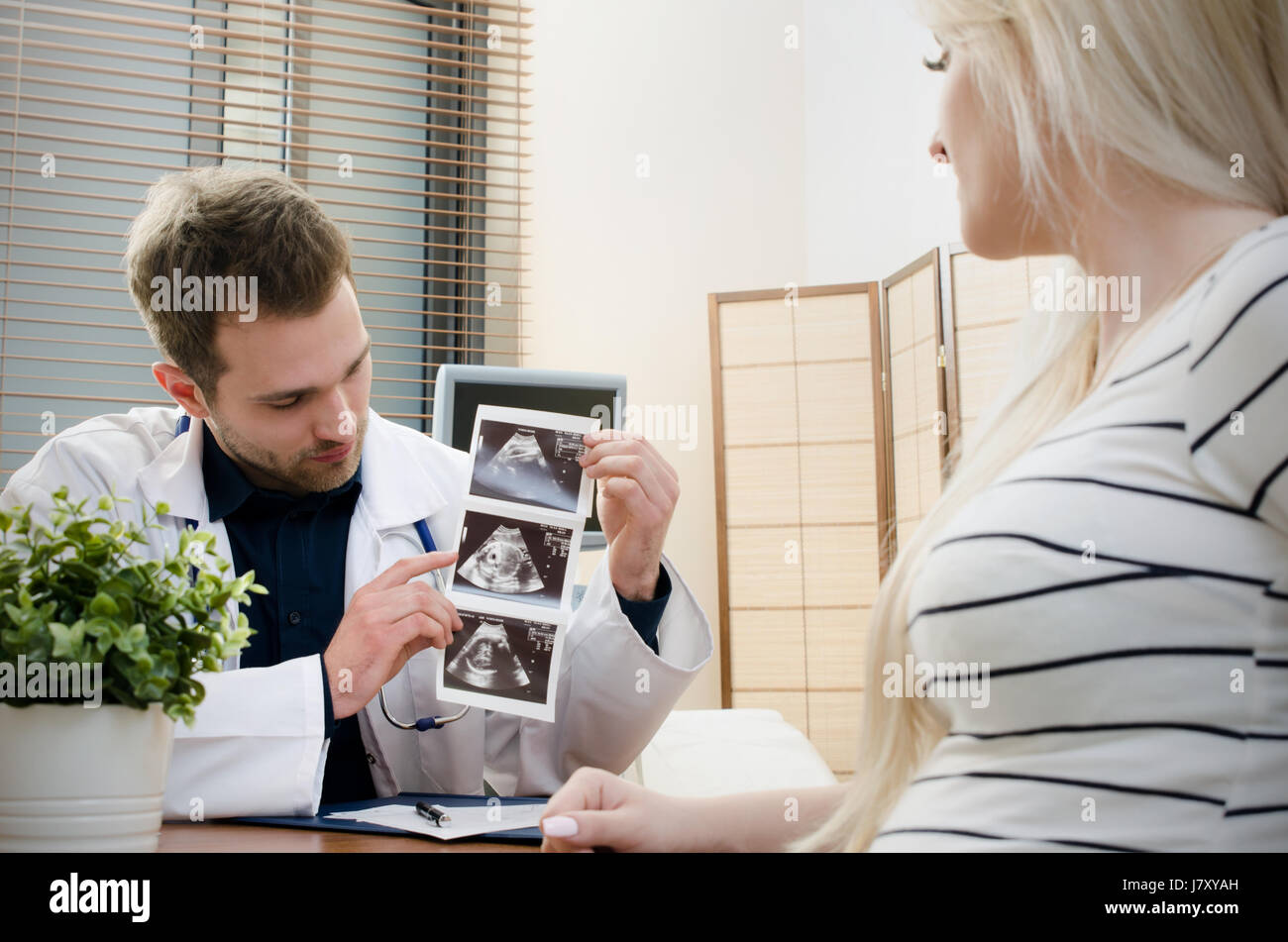 Doctor showing baby ultrasound image to pregnant woman. showing ...