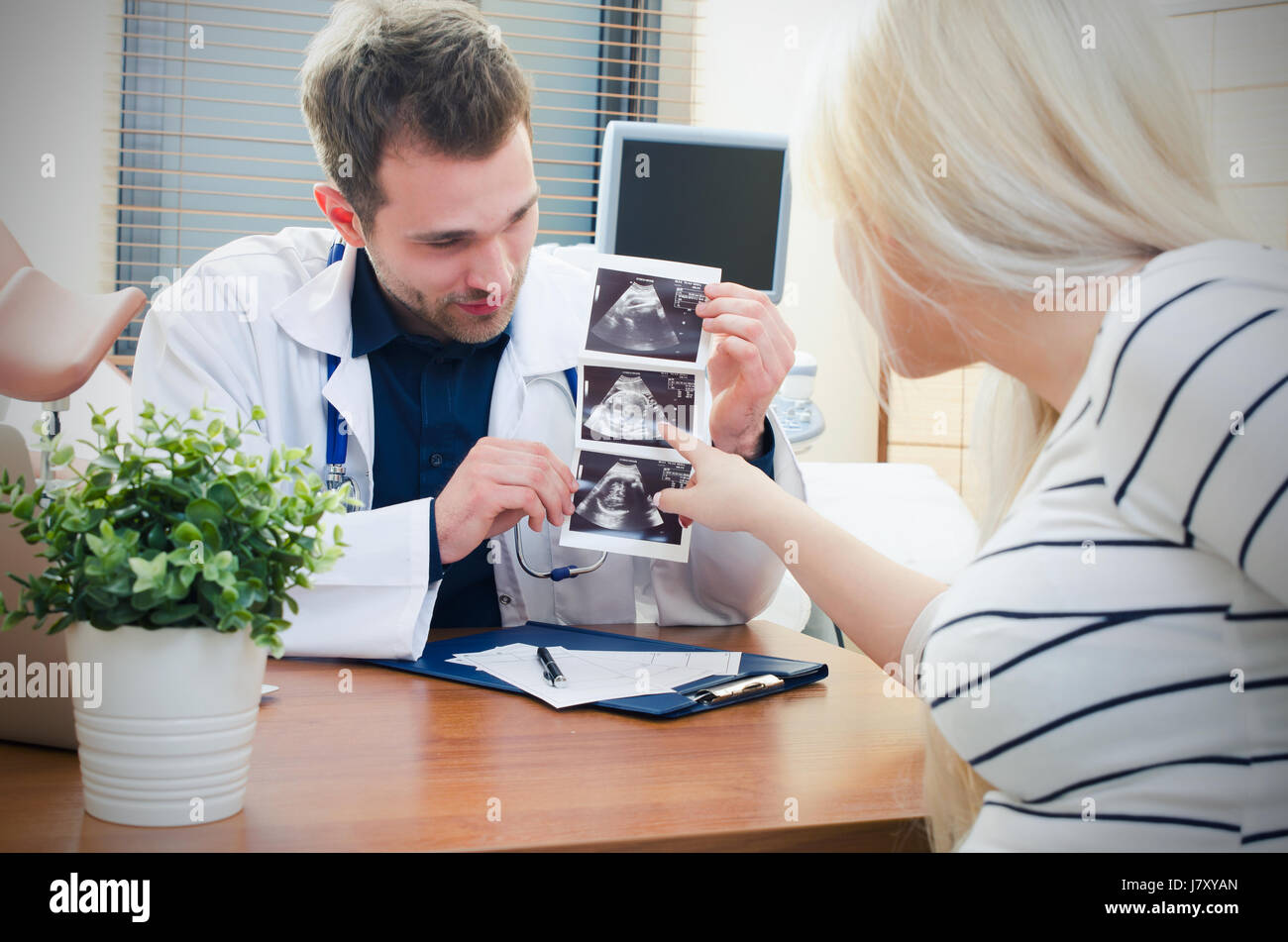 Doctor showing baby ultrasound image to pregnant woman. showing ...