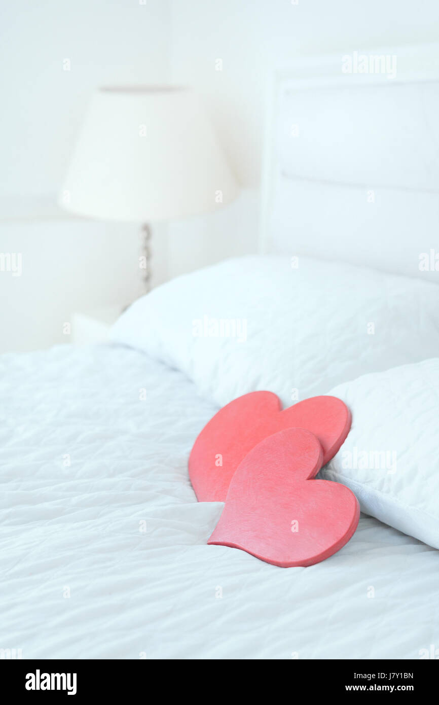Two red heart symbols on white bed Stock Photo - Alamy