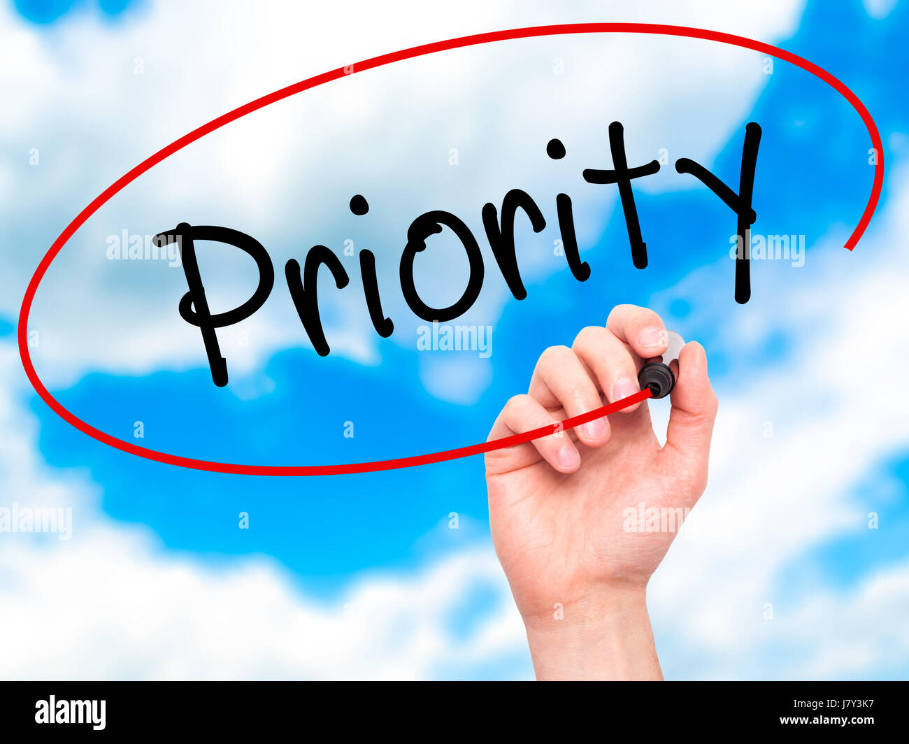 Man Hand writing Priority with marker on transparent wipe board ...