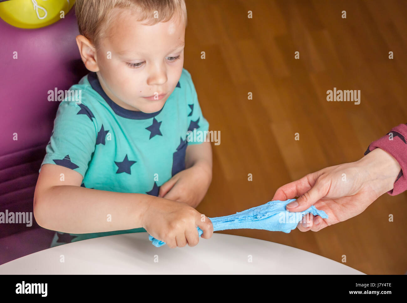 cute boy stretching big blue piece of plasticine Stock Photo - Alamy