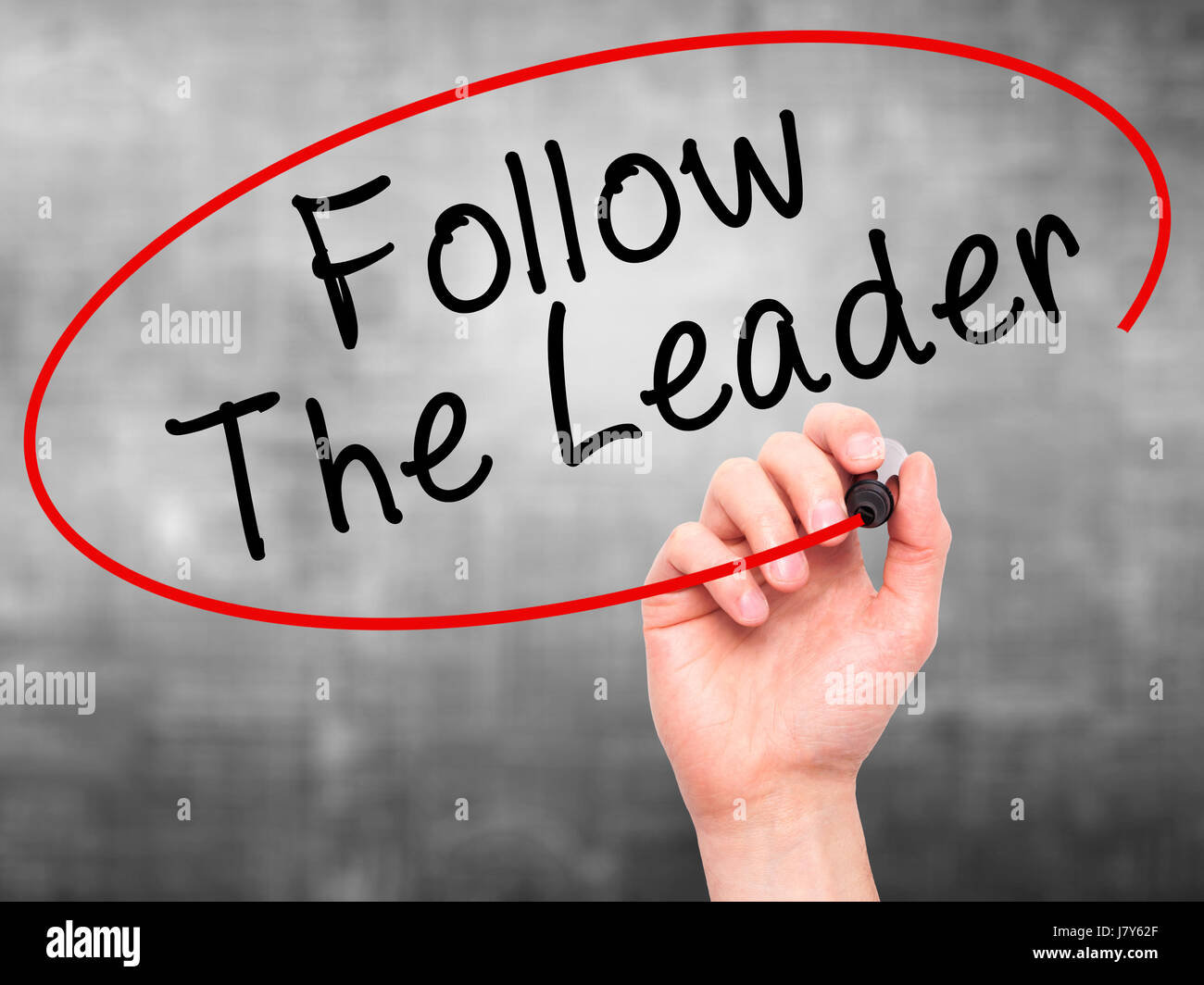 Man Hand writing Follow The Leader with black marker on visual screen ...