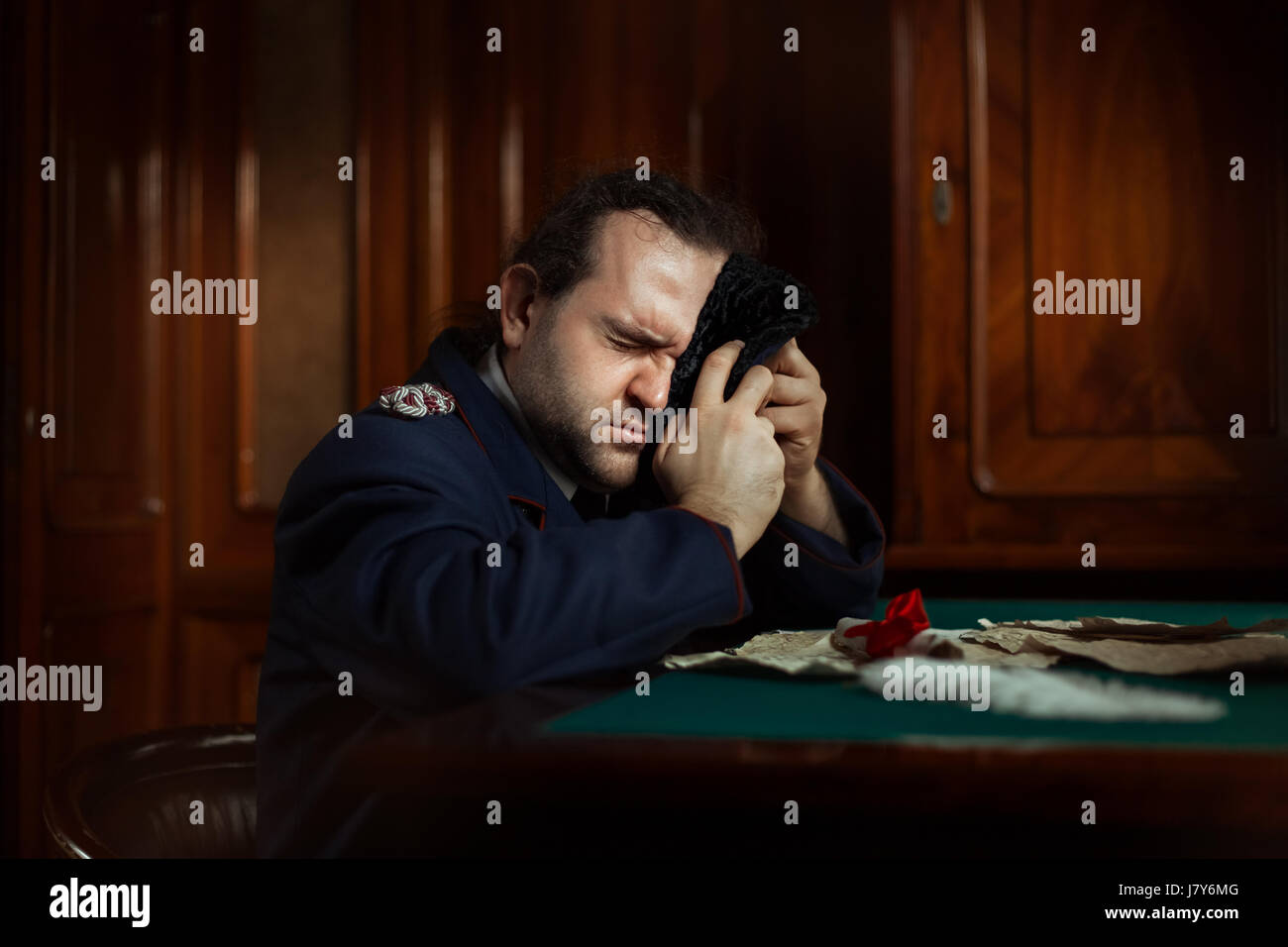 Man sitting at the table crying. On the table are his letters, retro ...