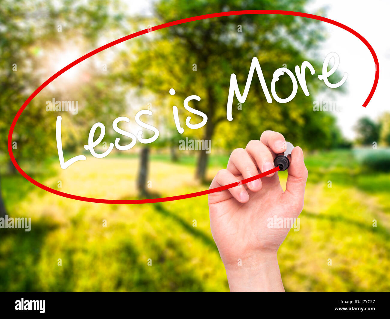 Man Hand writing Less is More with black marker on visual screen ...