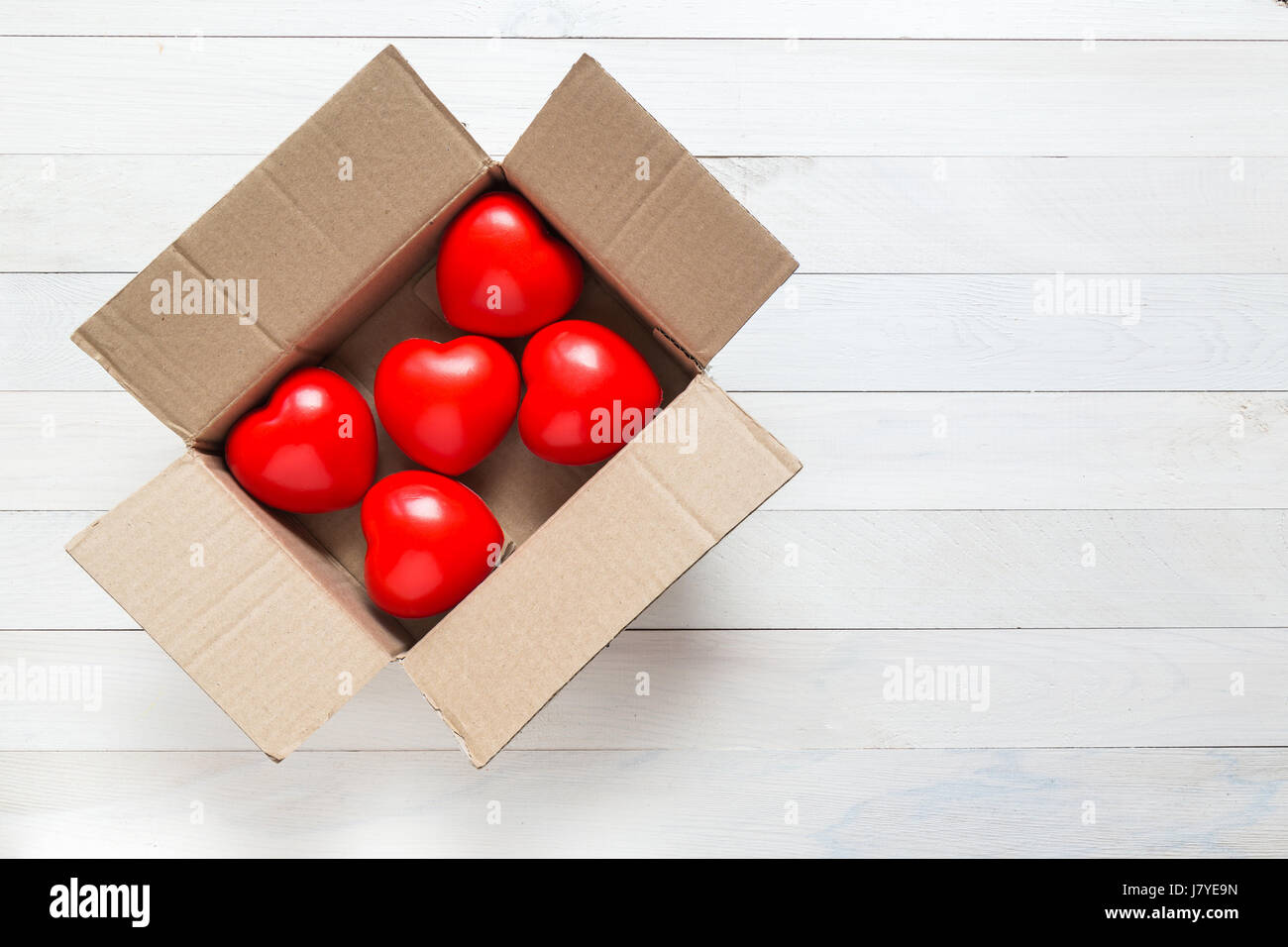 Top view red heart in brown box on white wooden plank background. For ...