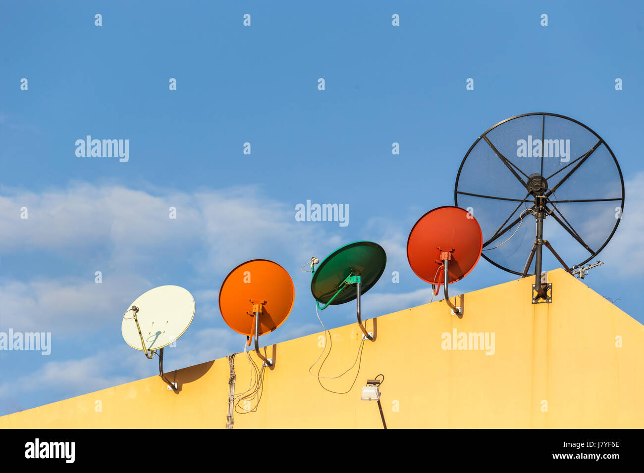 Several satellite dish installed on the house roof with blue sky ...