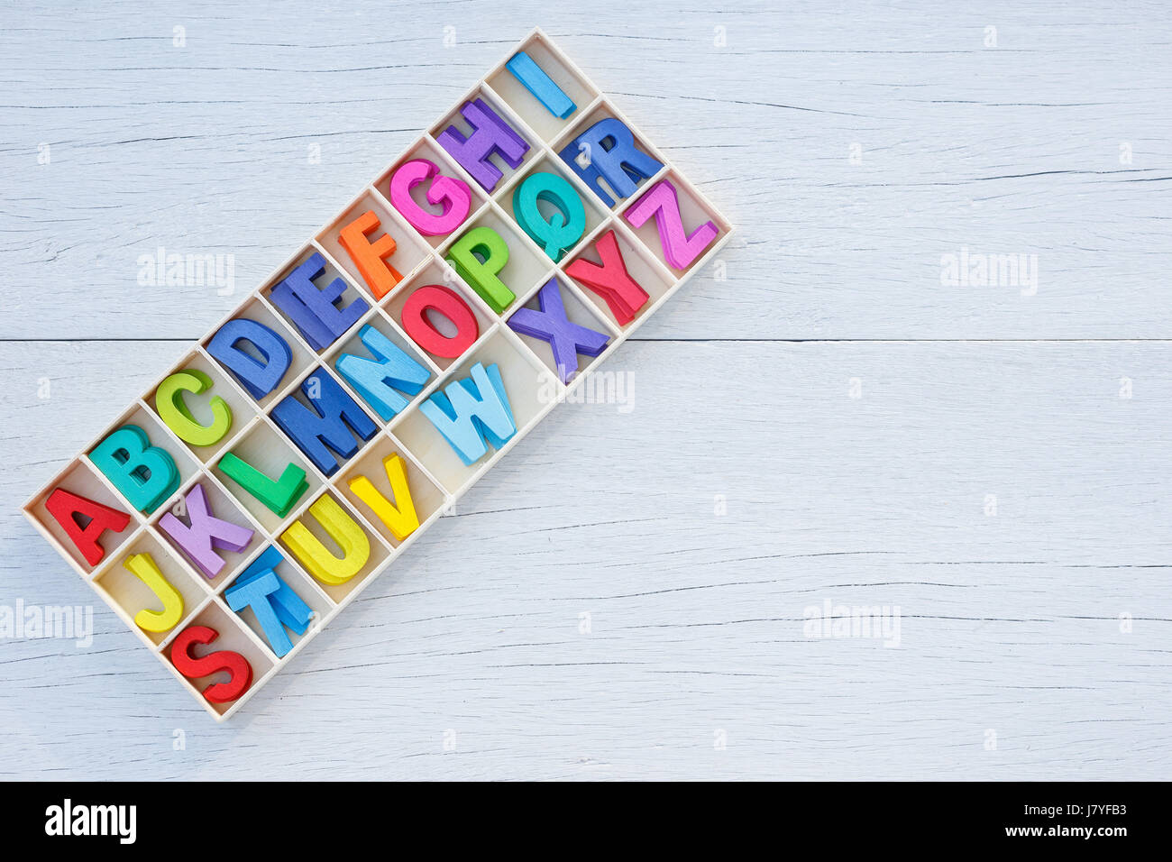 Colorful wooden alphabet in square box. Top view on white wooden ...