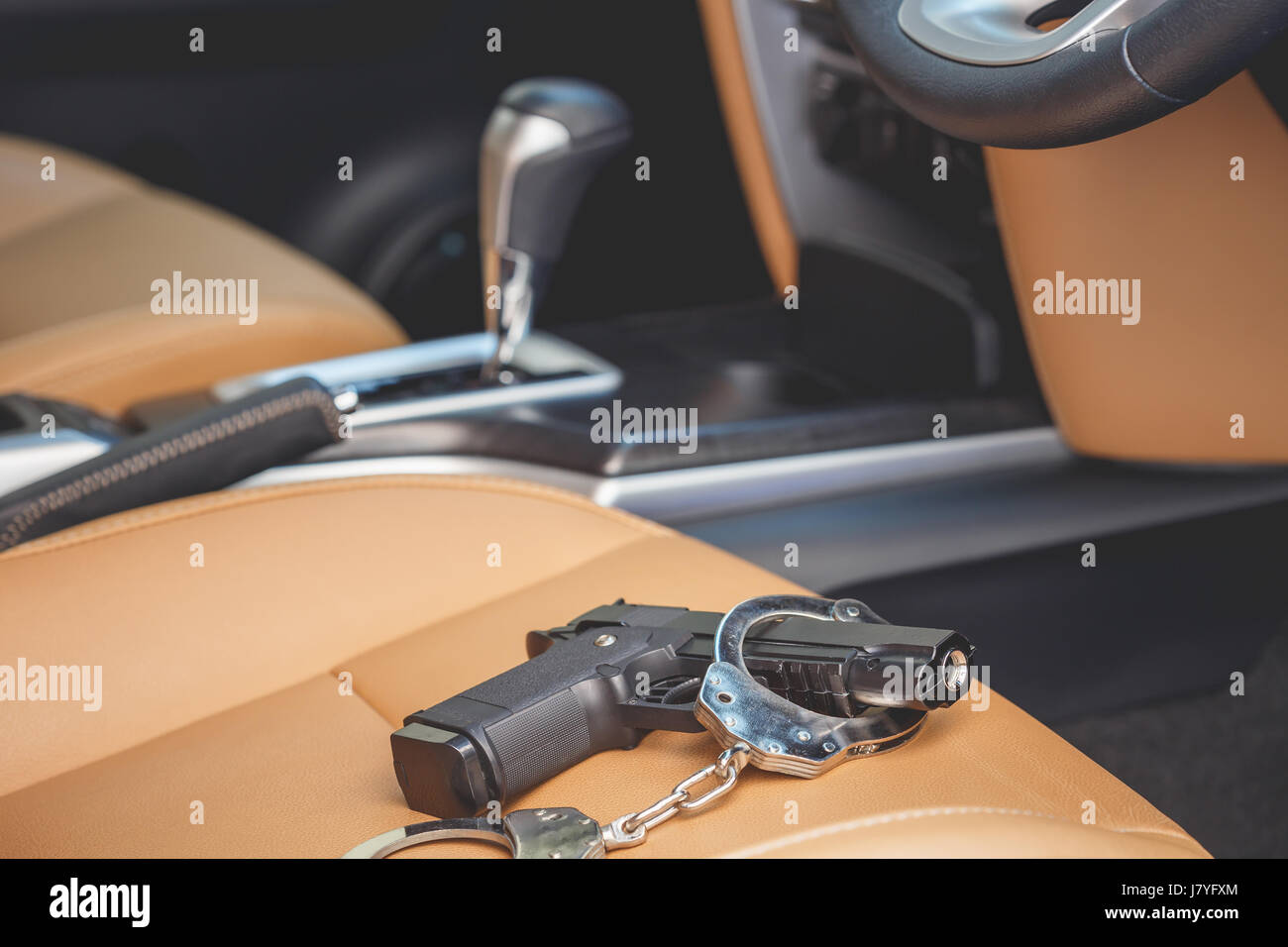 Close up black gun and handcuff inside the car. For violence on the ...