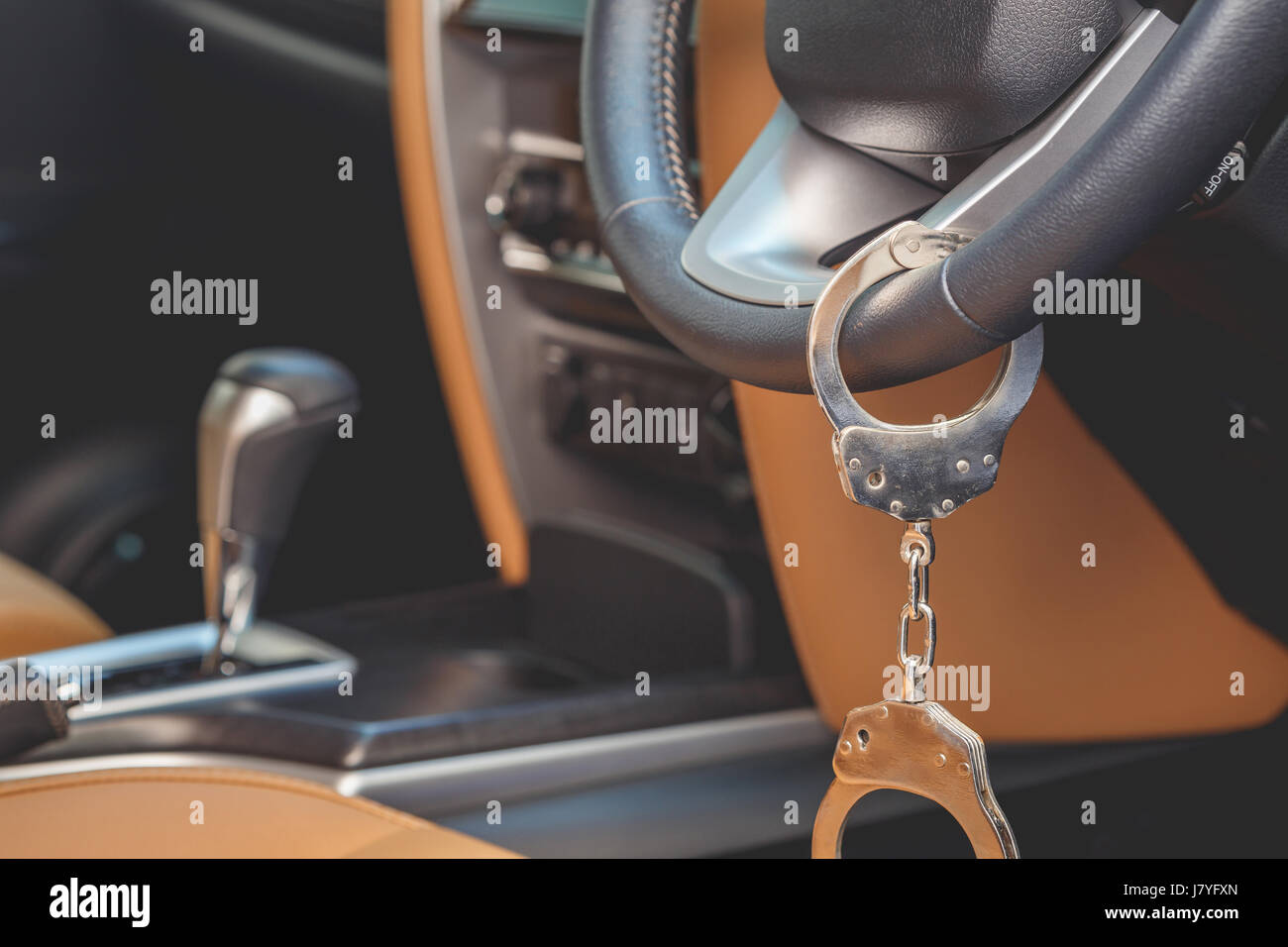Close up handcuff on steering wheel inside the car. For violence on the ...