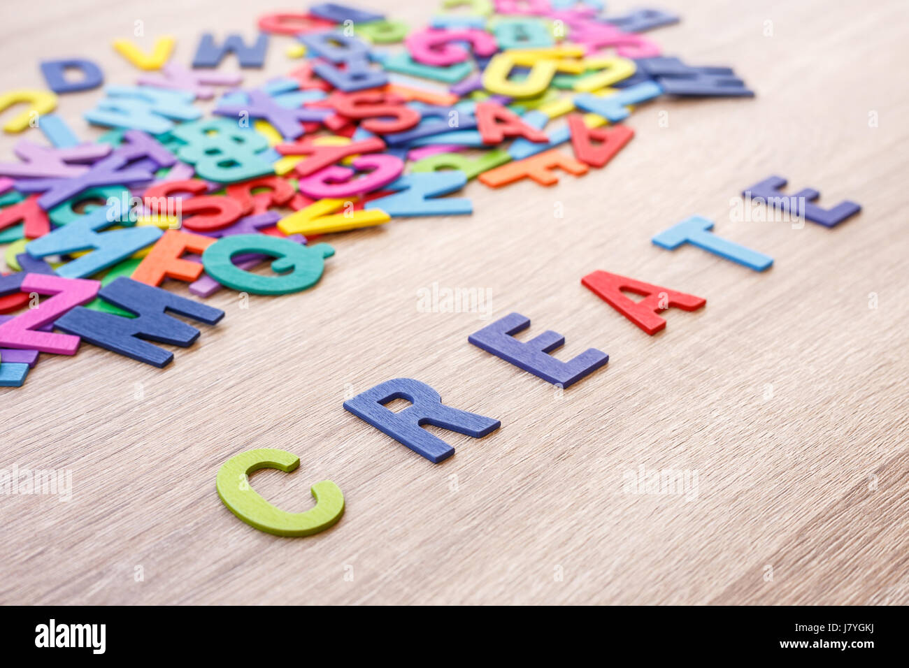 Colorful wooden alphabet and word "CREATE". Top view on grey wooden ...