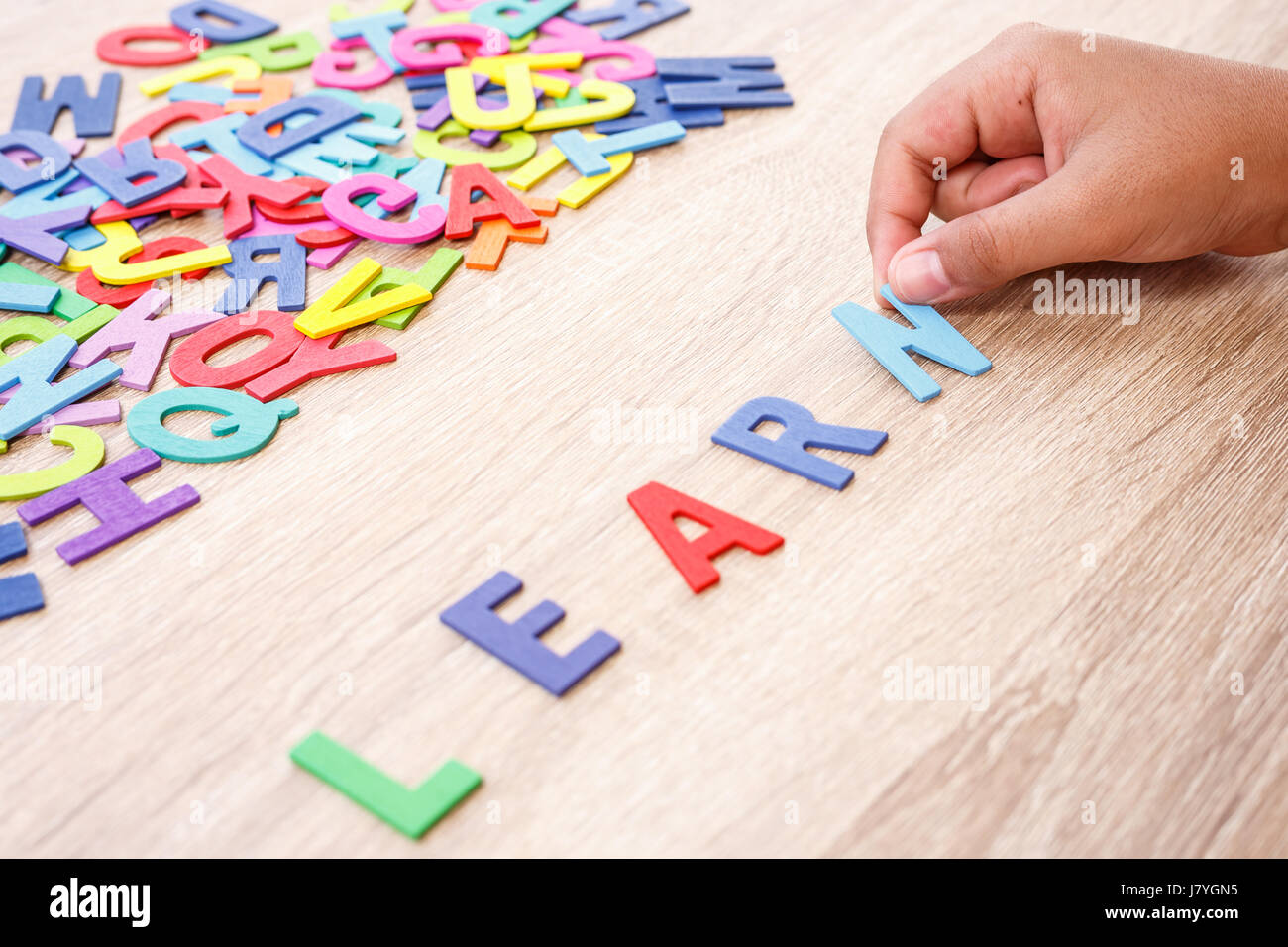 Colorful wooden alphabet and word "LEARN", Hand sort on N. Top view on ...