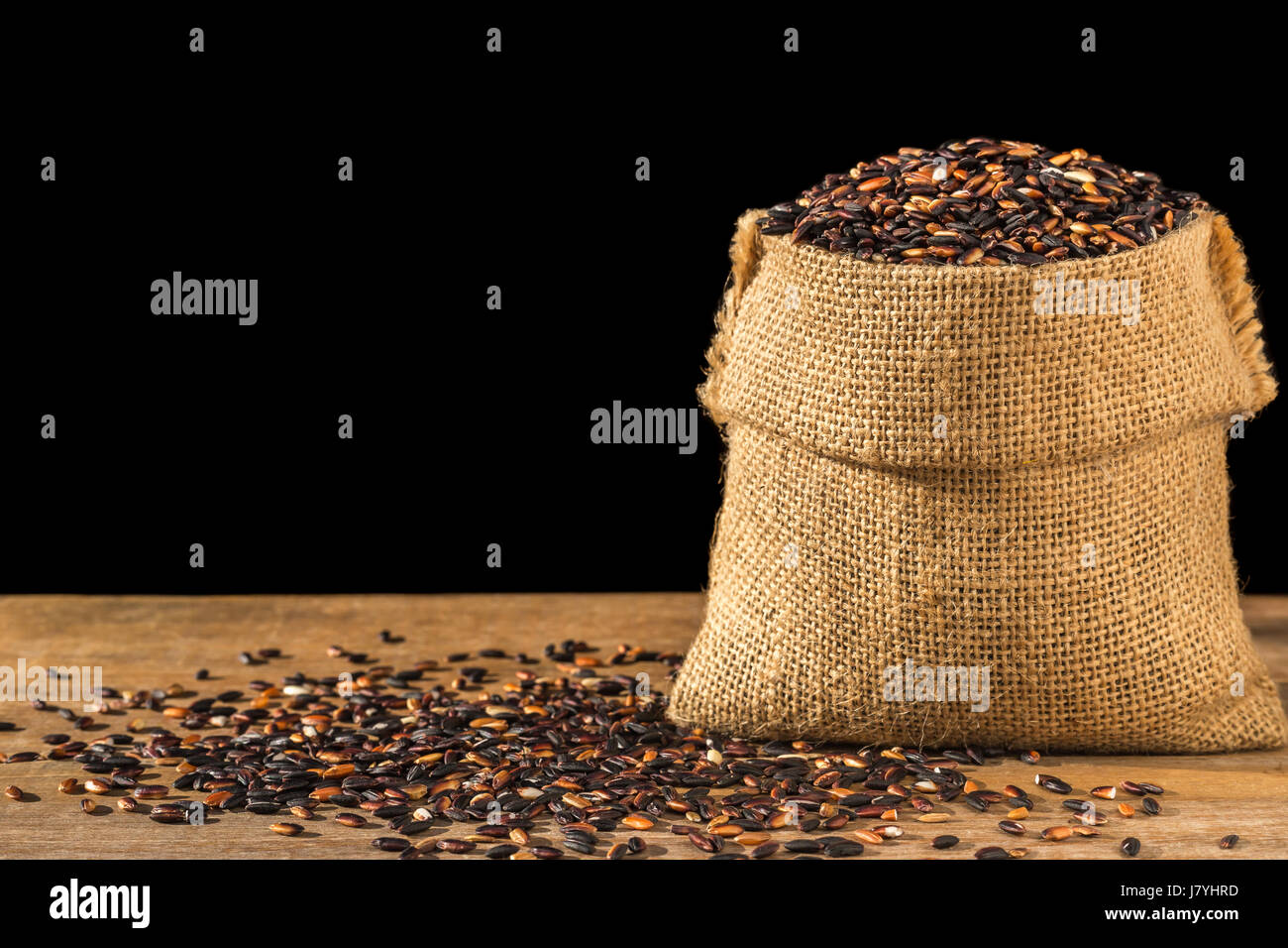 Close up Thai black sticky rice in small sack on wooden table. Isolated ...