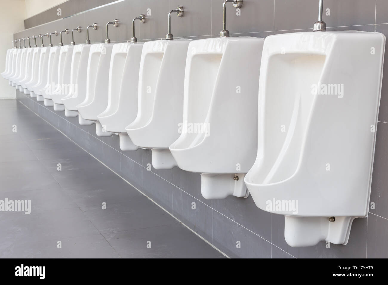 New row of outdoor urinals on grey wall in men public toilet Stock ...